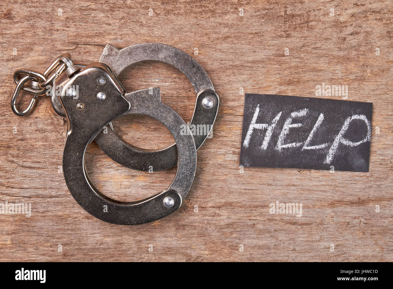 Metal handcuffs isolated on wooden background Stock Photo - Alamy