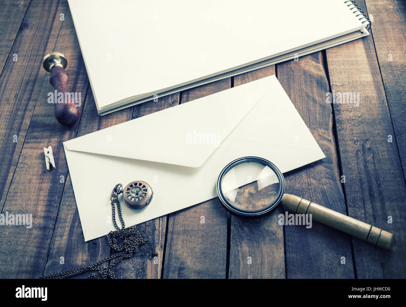 Blank paper envelope, magnifier, stamp and clock on vintage wood table background. Template for ...