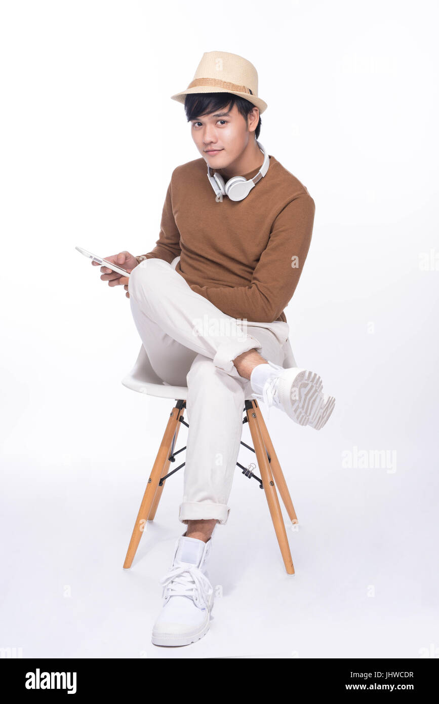 Smart casual asian man seated on chair, holding smartphone in studio ...