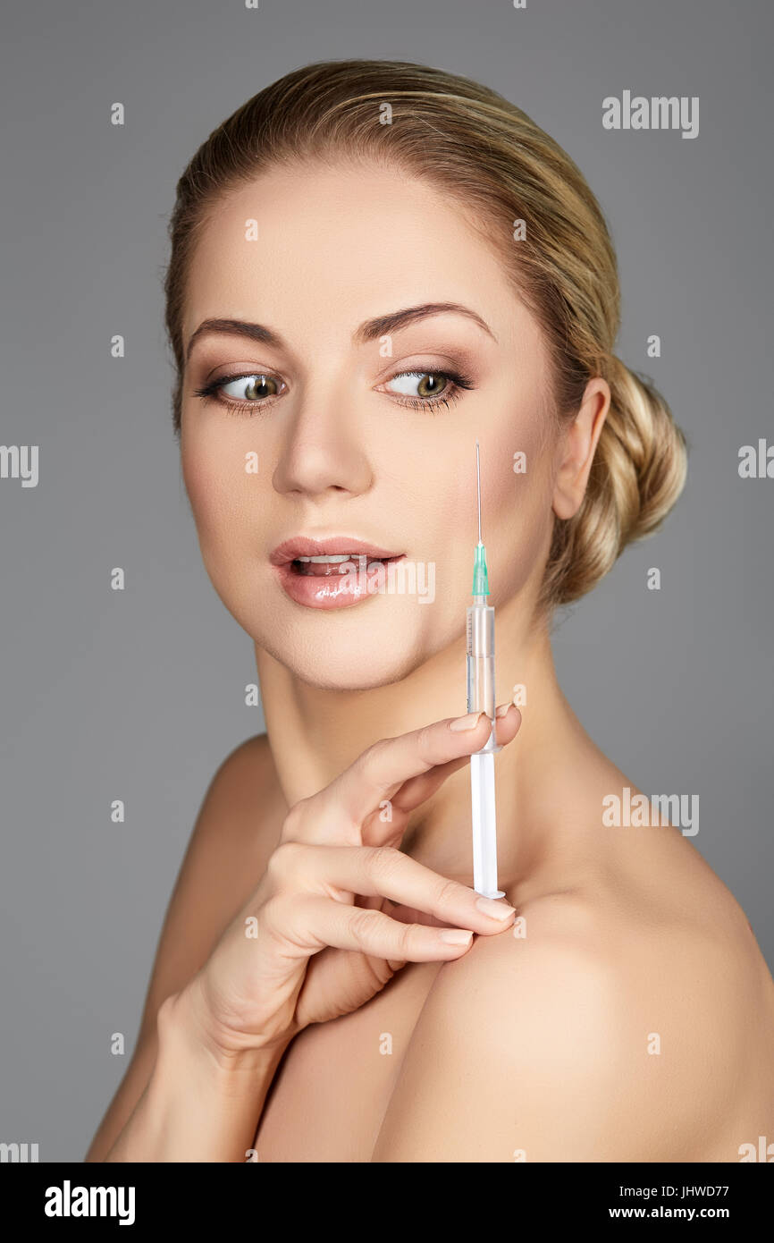 beautiful young woman holding syringe with collagen treatment injection ...