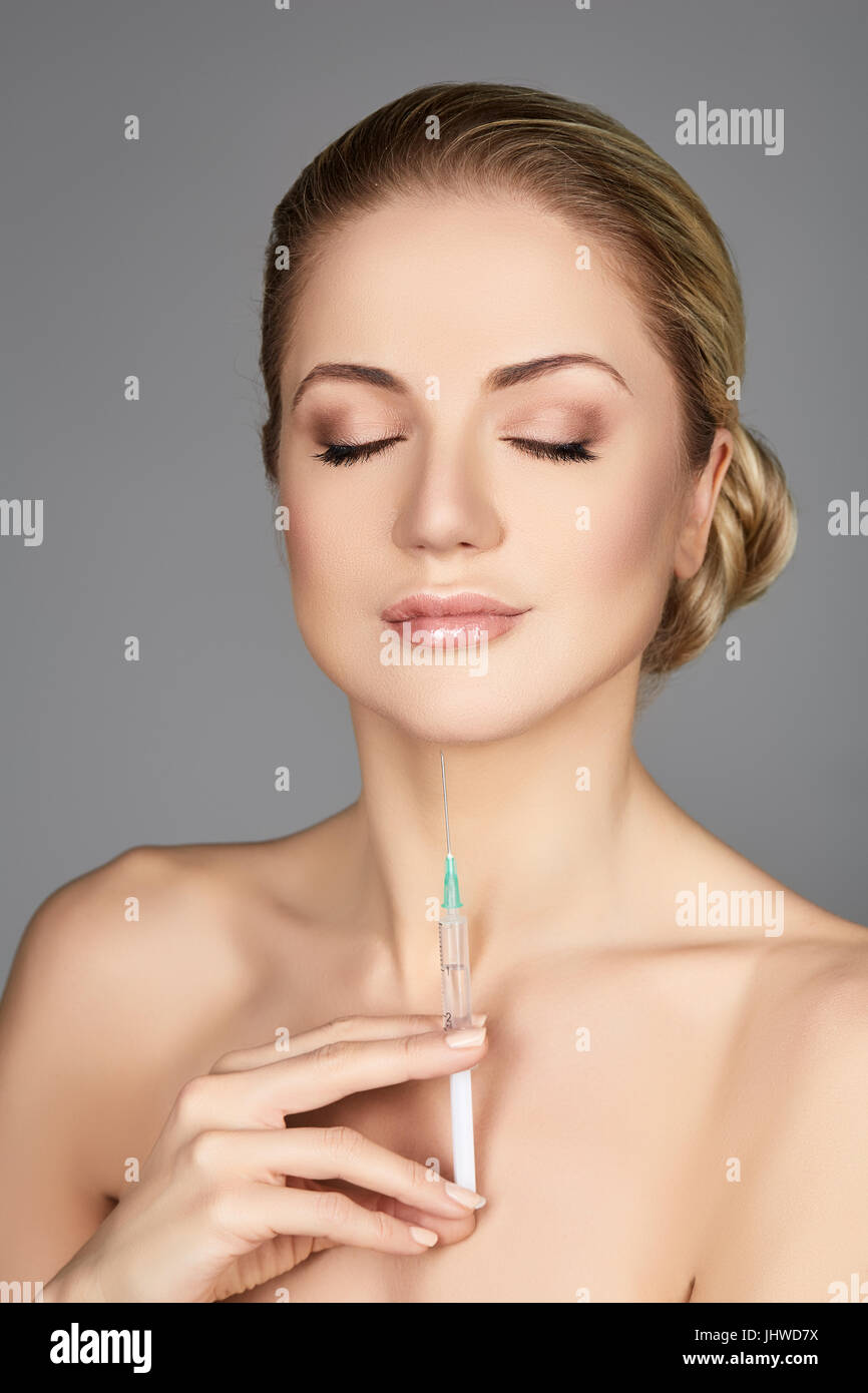 beautiful young woman holding syringe with collagen treatment injection ...