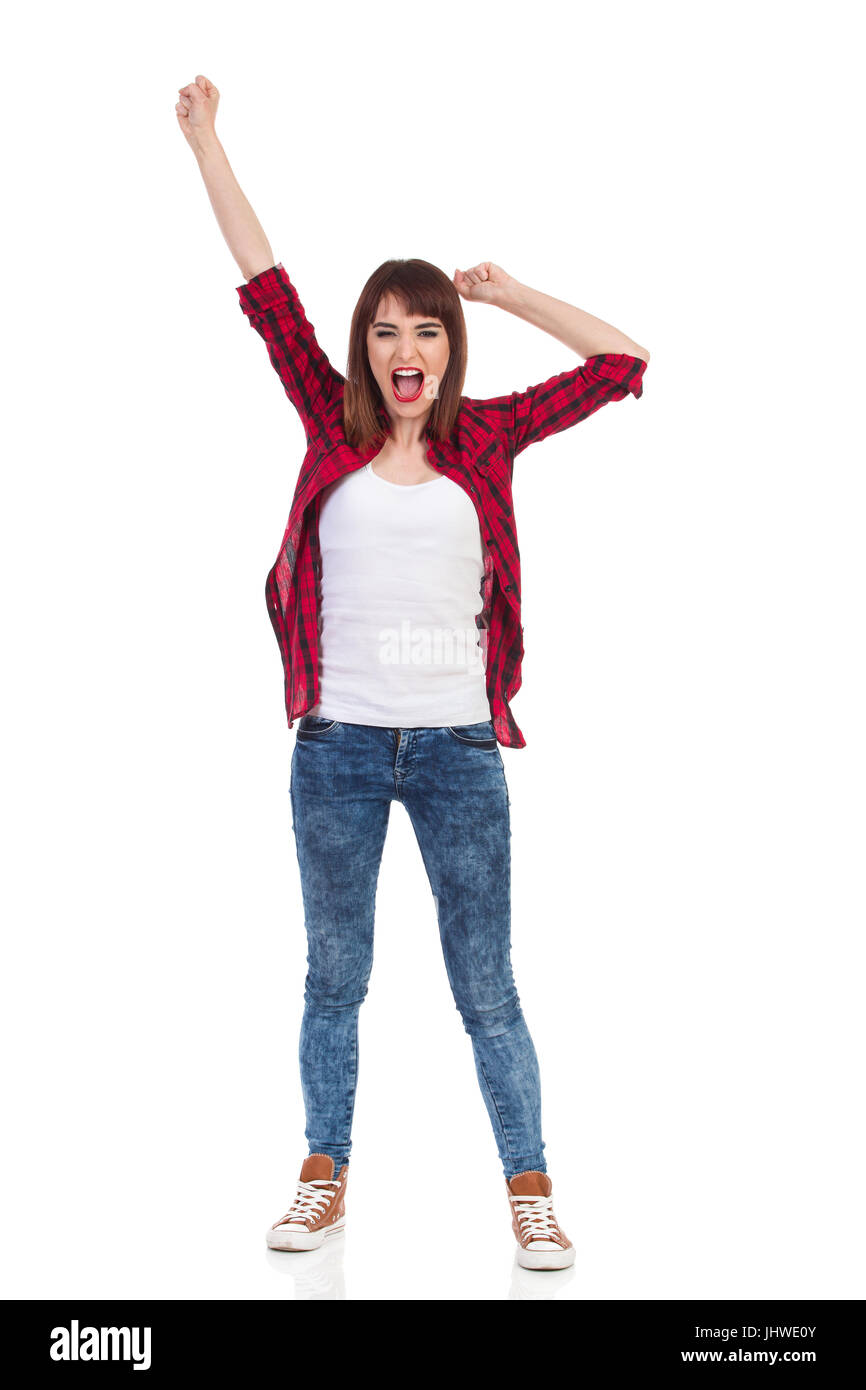 Shouting young woman in red lumberjack shirt, jeans and brown sneakers ...
