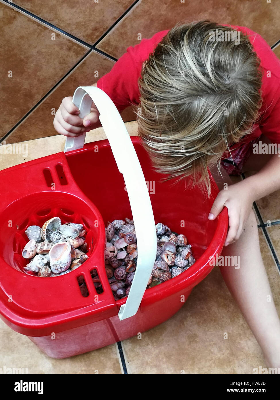 Boy with a red cape full of shells Stock Photo - Alamy