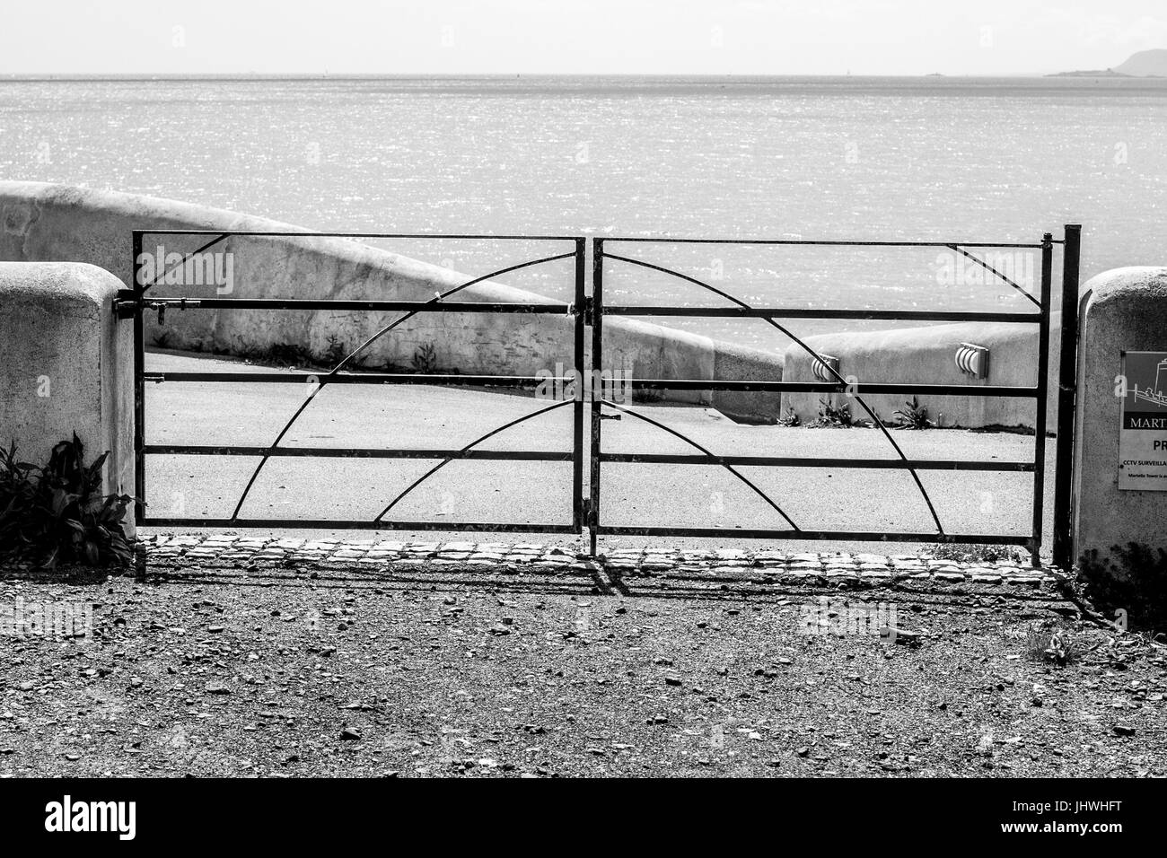 Wrought iron gate with semi-circle design against an ocean backdrop ...