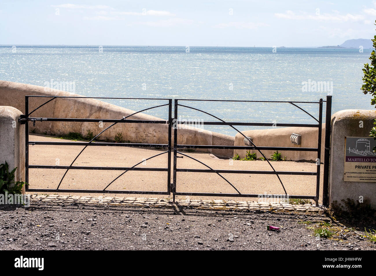 Wrought iron gate with semi-circle design against an ocean backdrop ...
