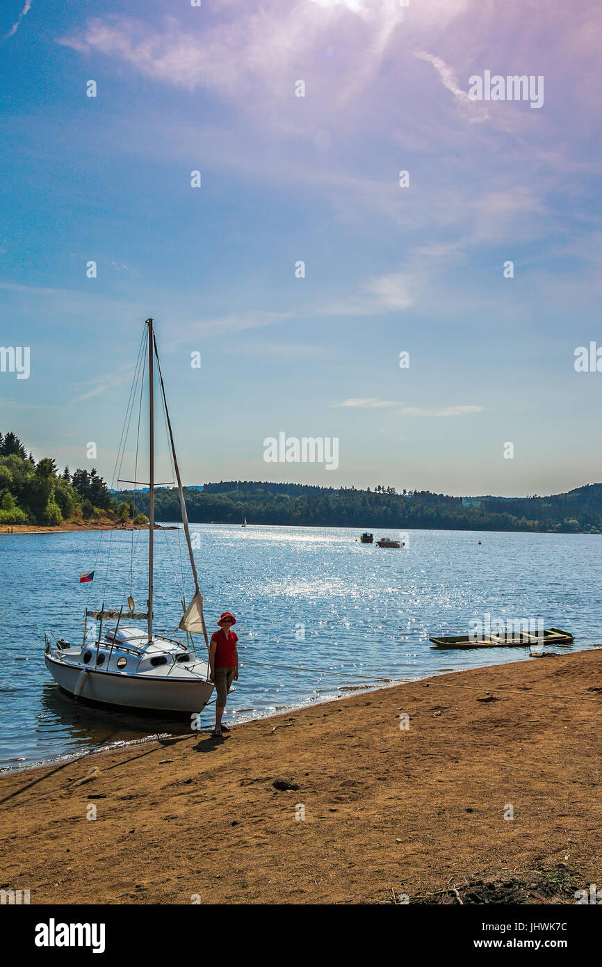 Small boat at shore of the small lake, late afternoon. Lake Orlik, 100 ...