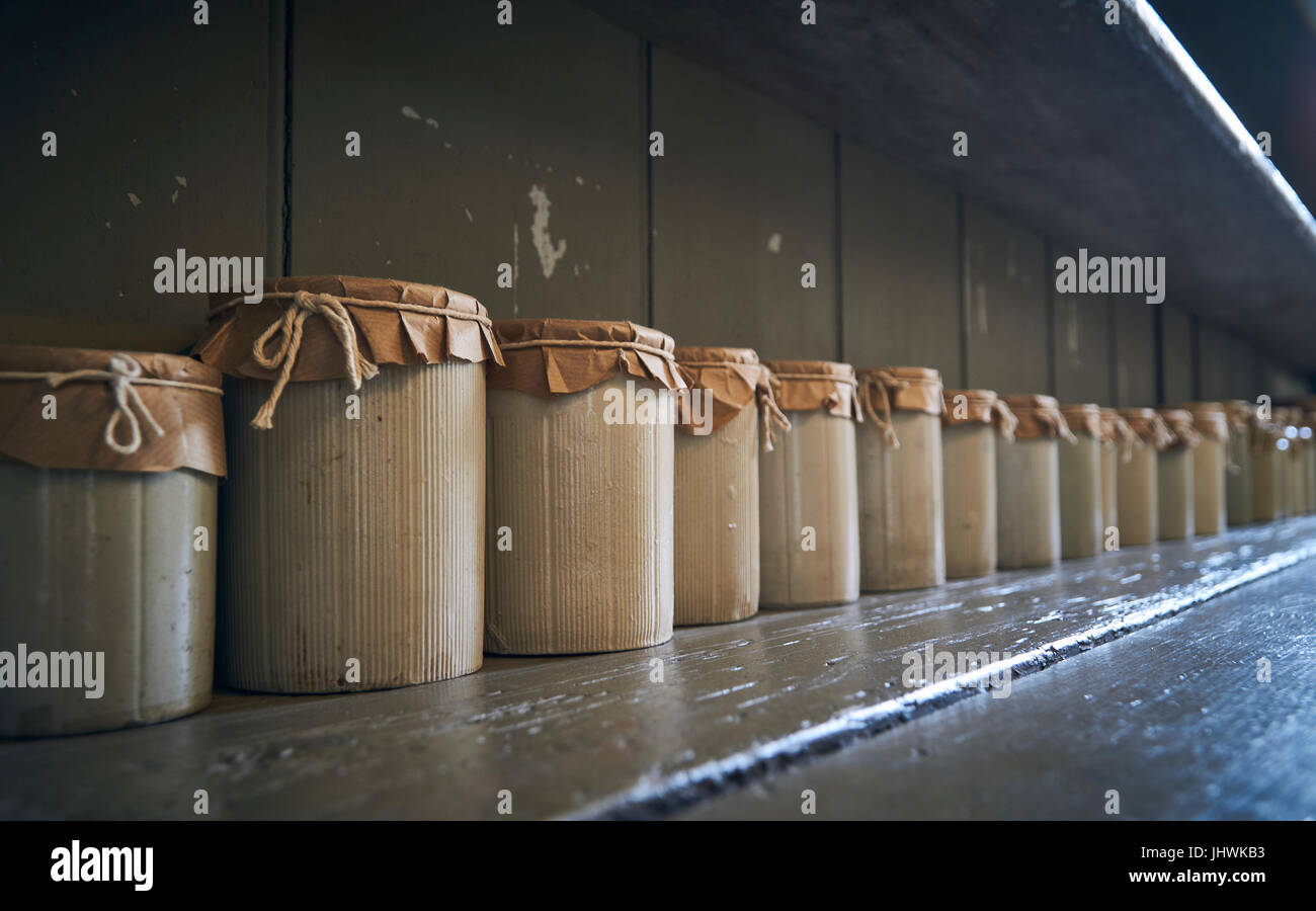 Traditional earthenware jam jars lined along a wooden shelf Stock Photo ...