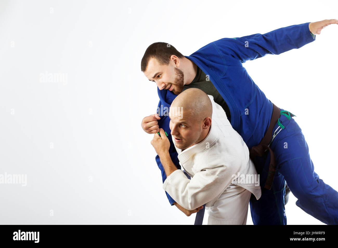 Two young men in a blue and white kimono fight judo , Jiu Jitsu on an ...