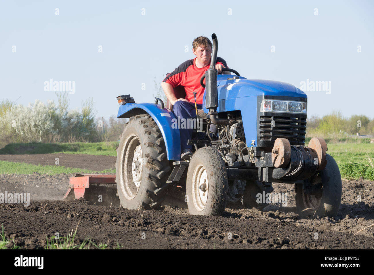 A farmer on a tractor lands a vegetable garden in the spring Stock ...