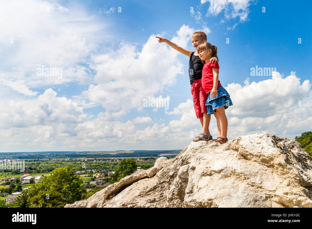 Little children boy and girl standing on mountain rock and looking ...