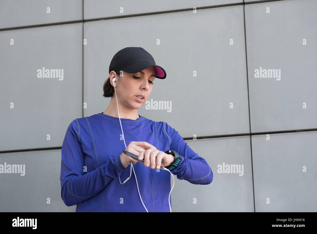 Fit woman checking time outside building Stock Photo - Alamy