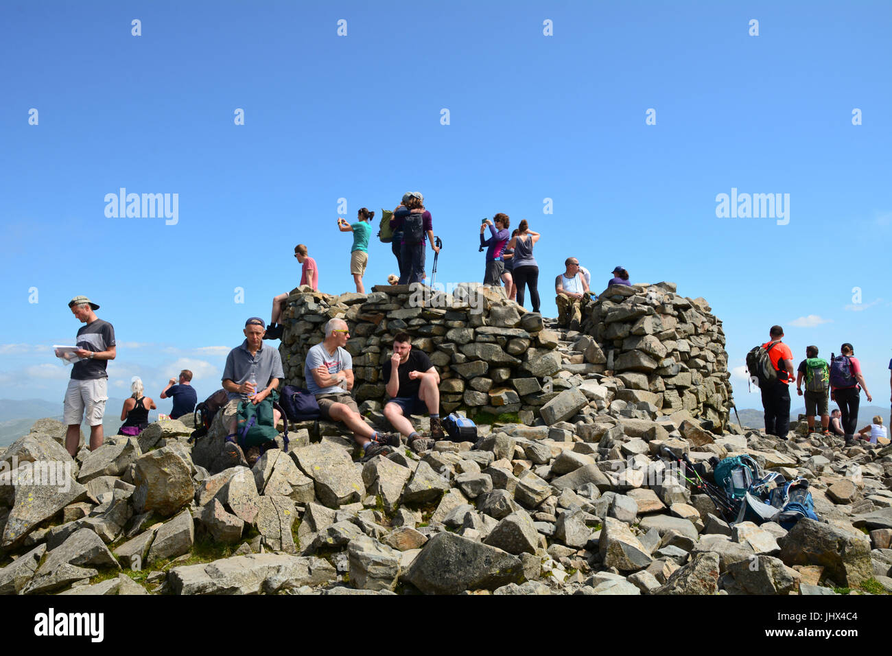 Hikers resting at the summit of Scafell PIke in the Lake District ...