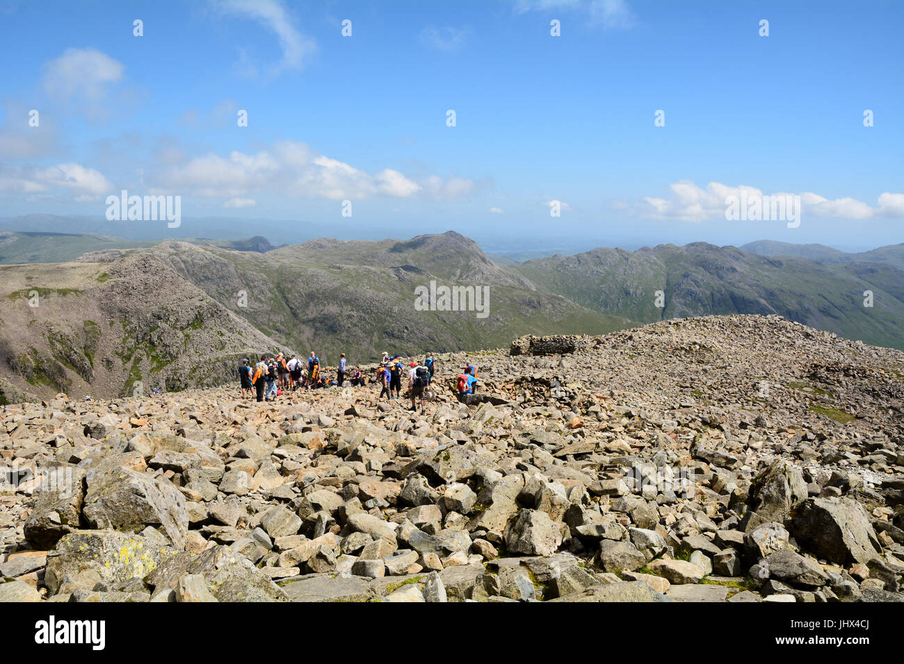 Hikers resting at the summit of Scafell PIke in the Lake District ...