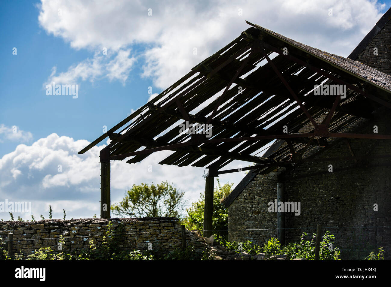 An old run down barn in a farmer's field with broken roof and old stone ...
