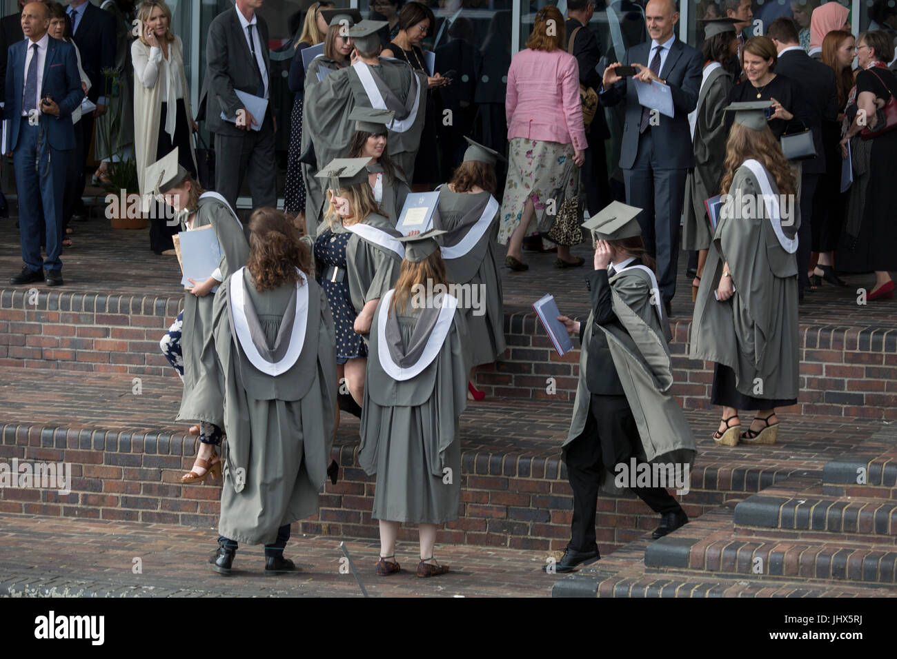 Young graduates wearing rented gowns and mortarboards have photos taken ...