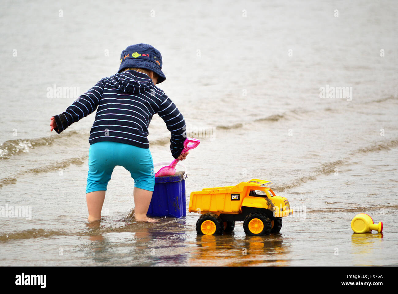 Little boy blue, building sandcastle with bucket, spade and his yellow ...