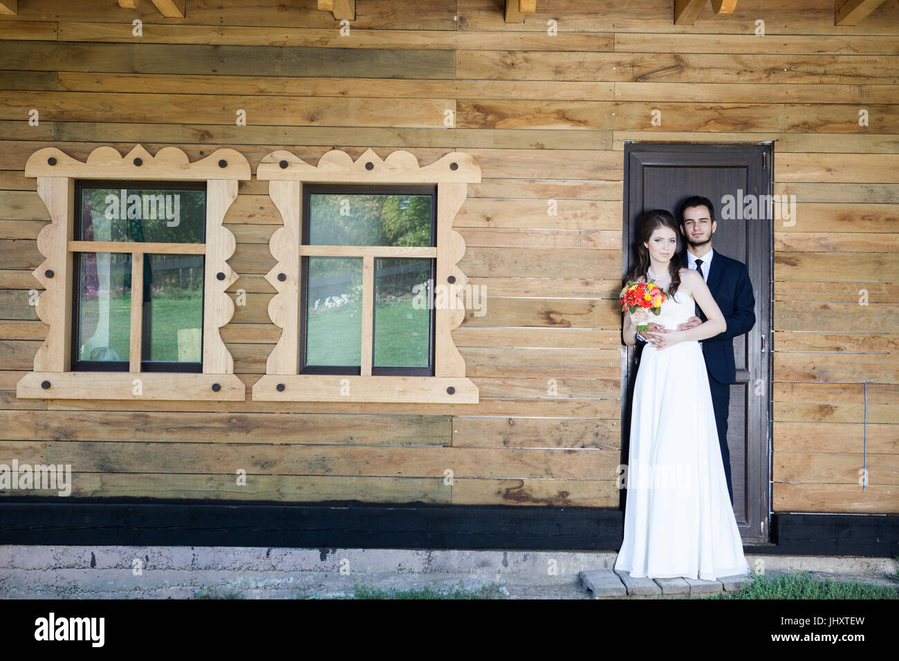 Beautiful young married couple posing next to a house Stock Photo - Alamy