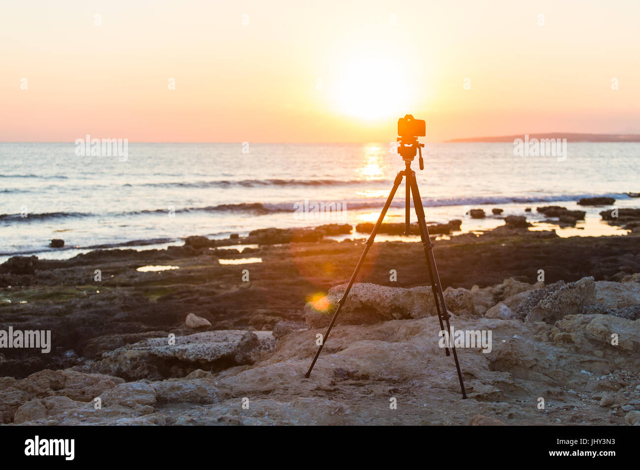 Camera with tripod over sun rising near the beach Stock Photo - Alamy