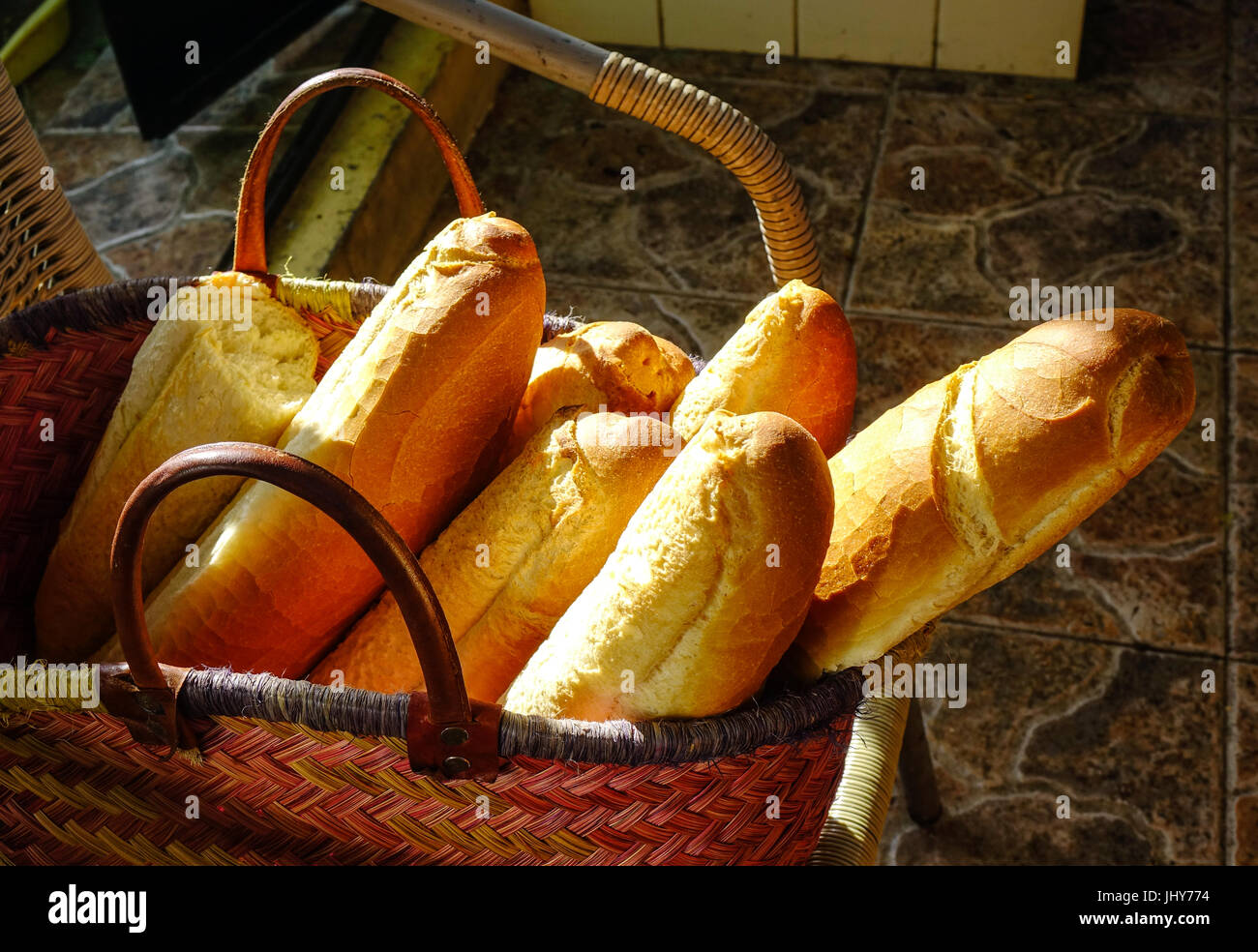 Fresh homemade bread under sun light in a wicker basket. Close up Stock ...