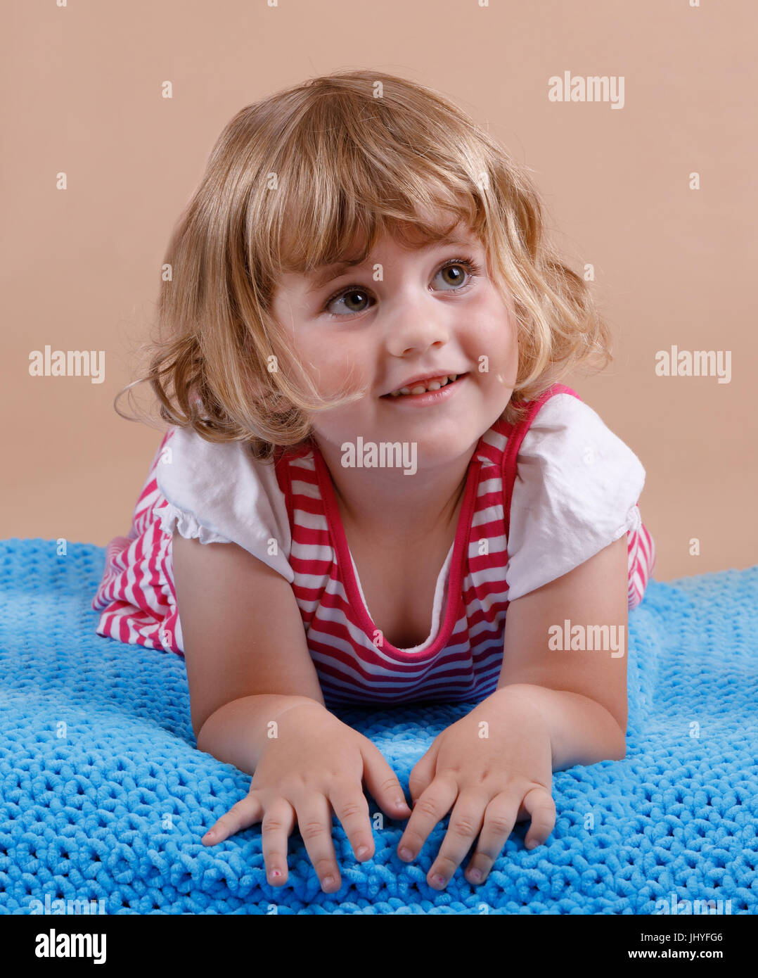 studio portrait of young cute baby girl, three years old on beige ...