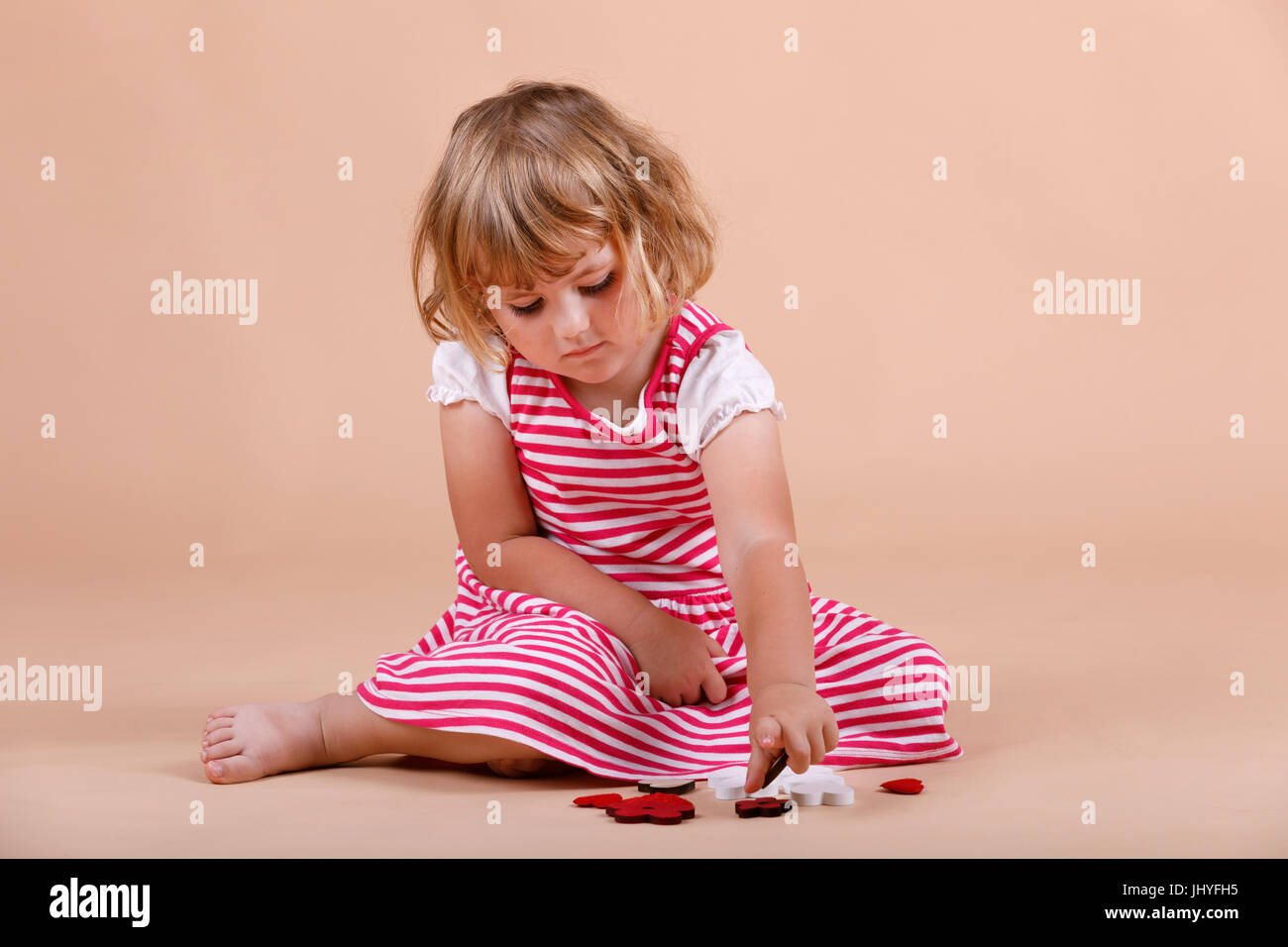 studio portrait of young cute baby girl, three years old on beige ...