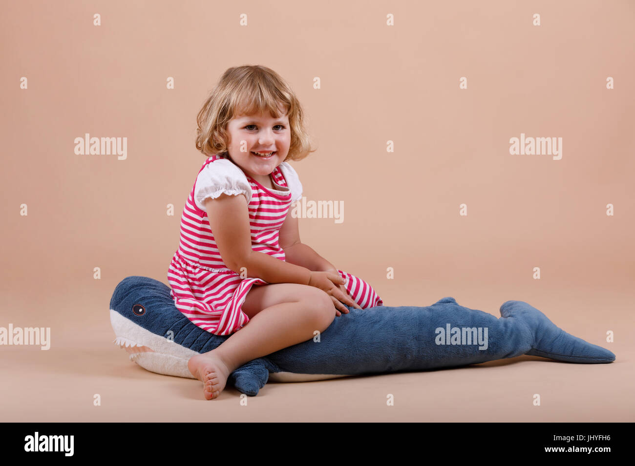 studio portrait of young cute baby girl, three years old on beige ...