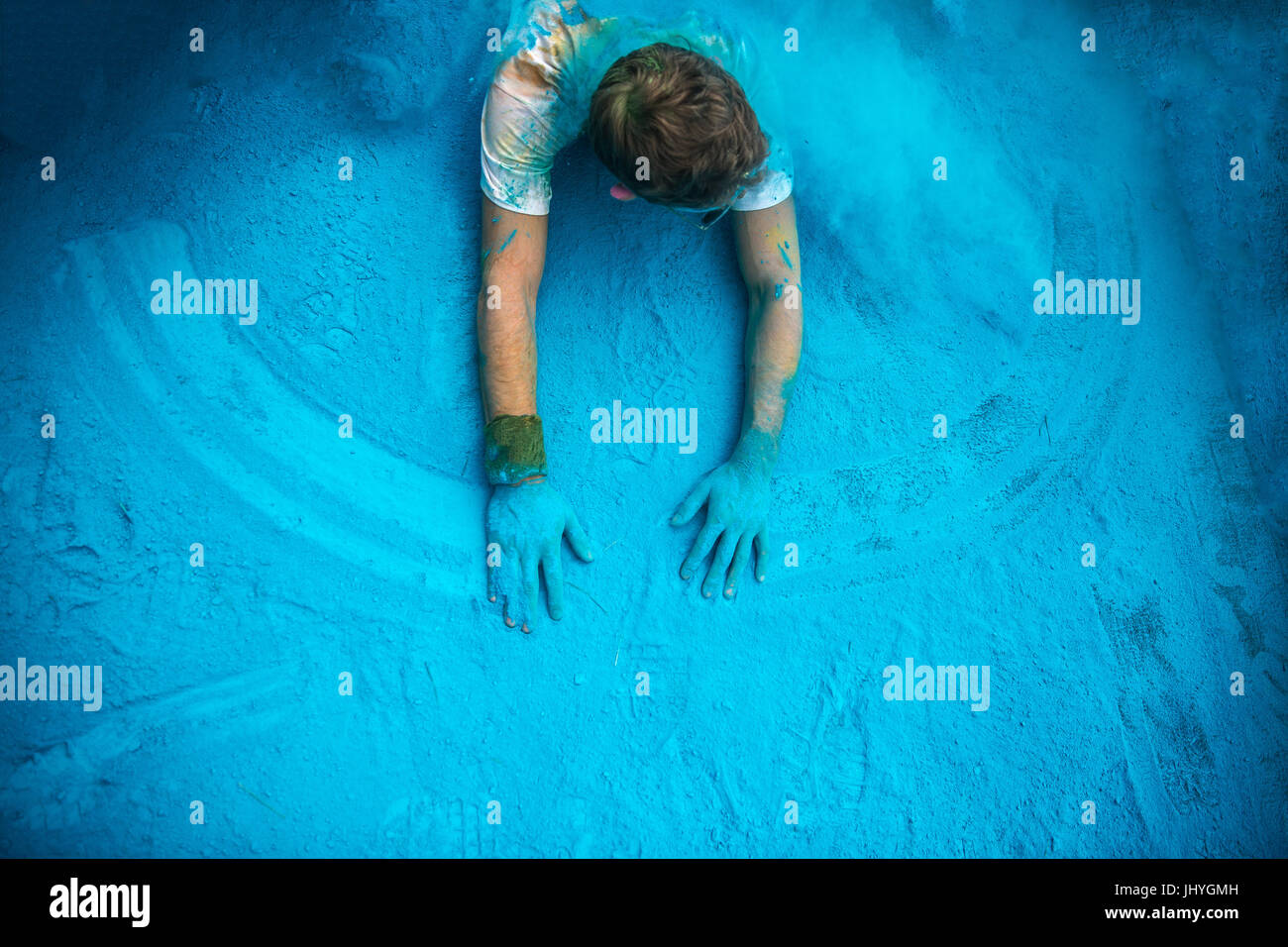 Kid playing with blue color on the ground Stock Photo - Alamy