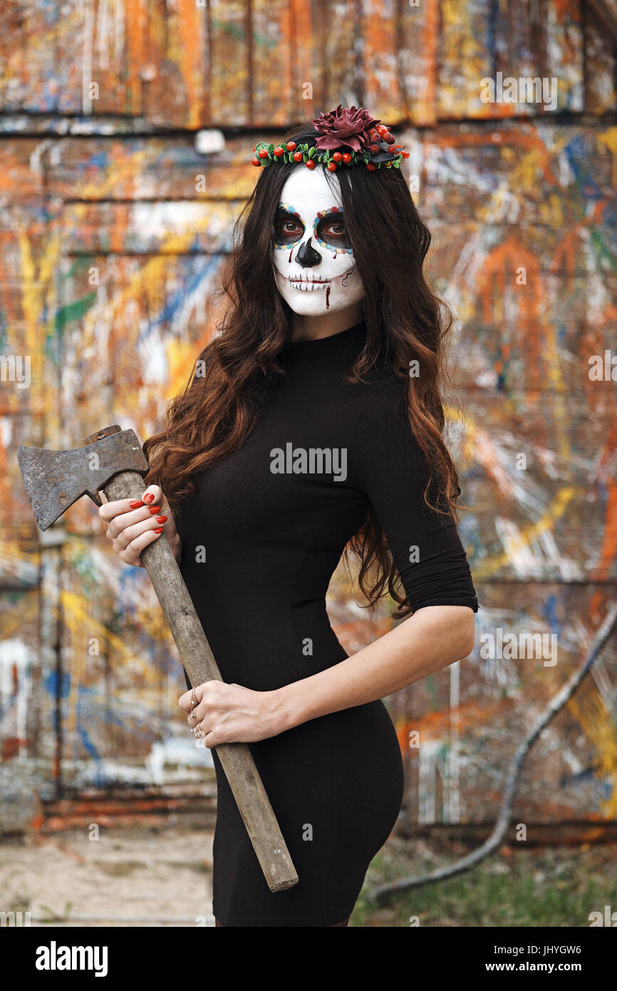 Female daemon with axe near painted barn. Face painting art Stock Photo ...