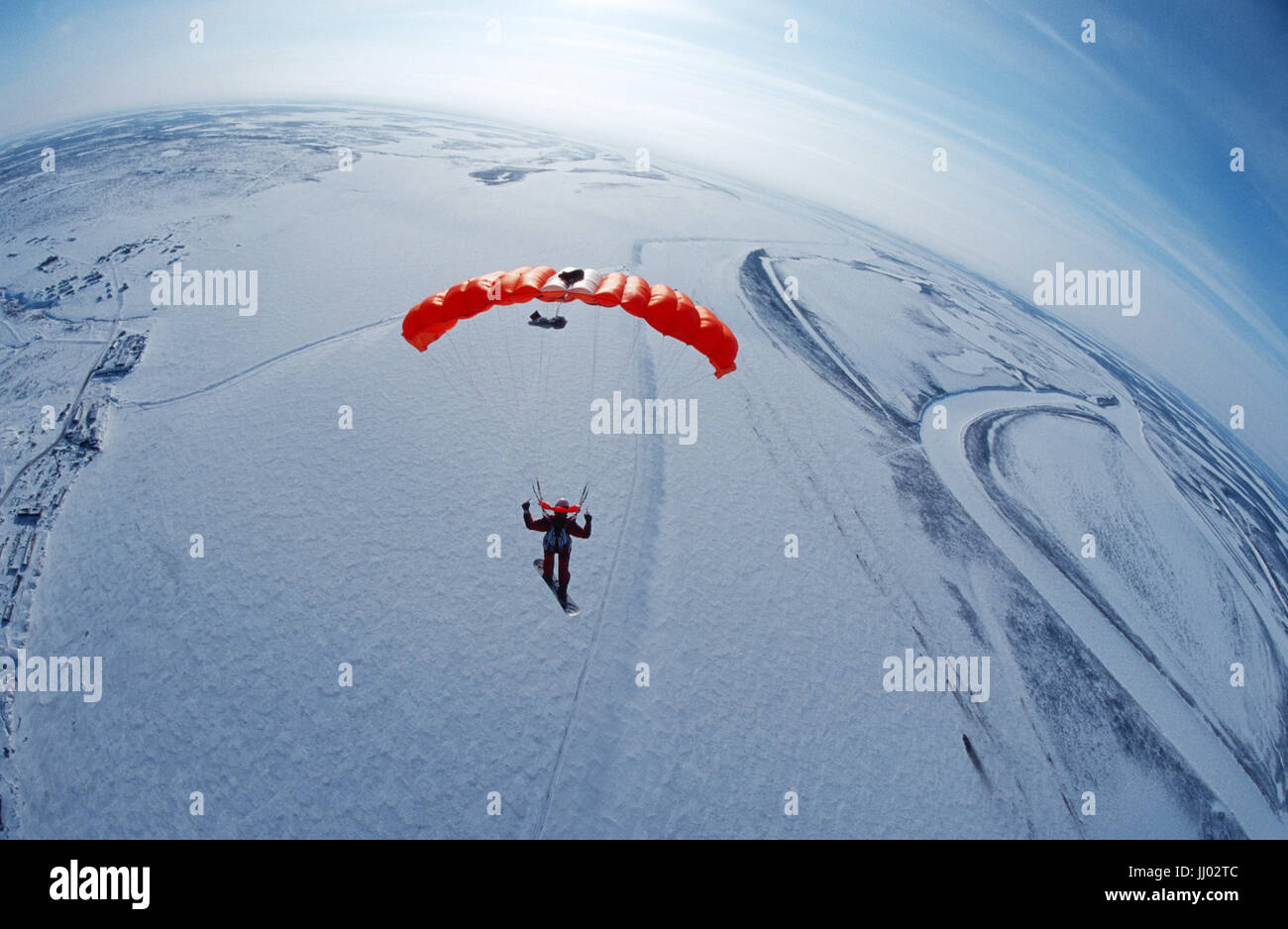 Skydiver flying her parachute above the the frozen tundra surrounding ...