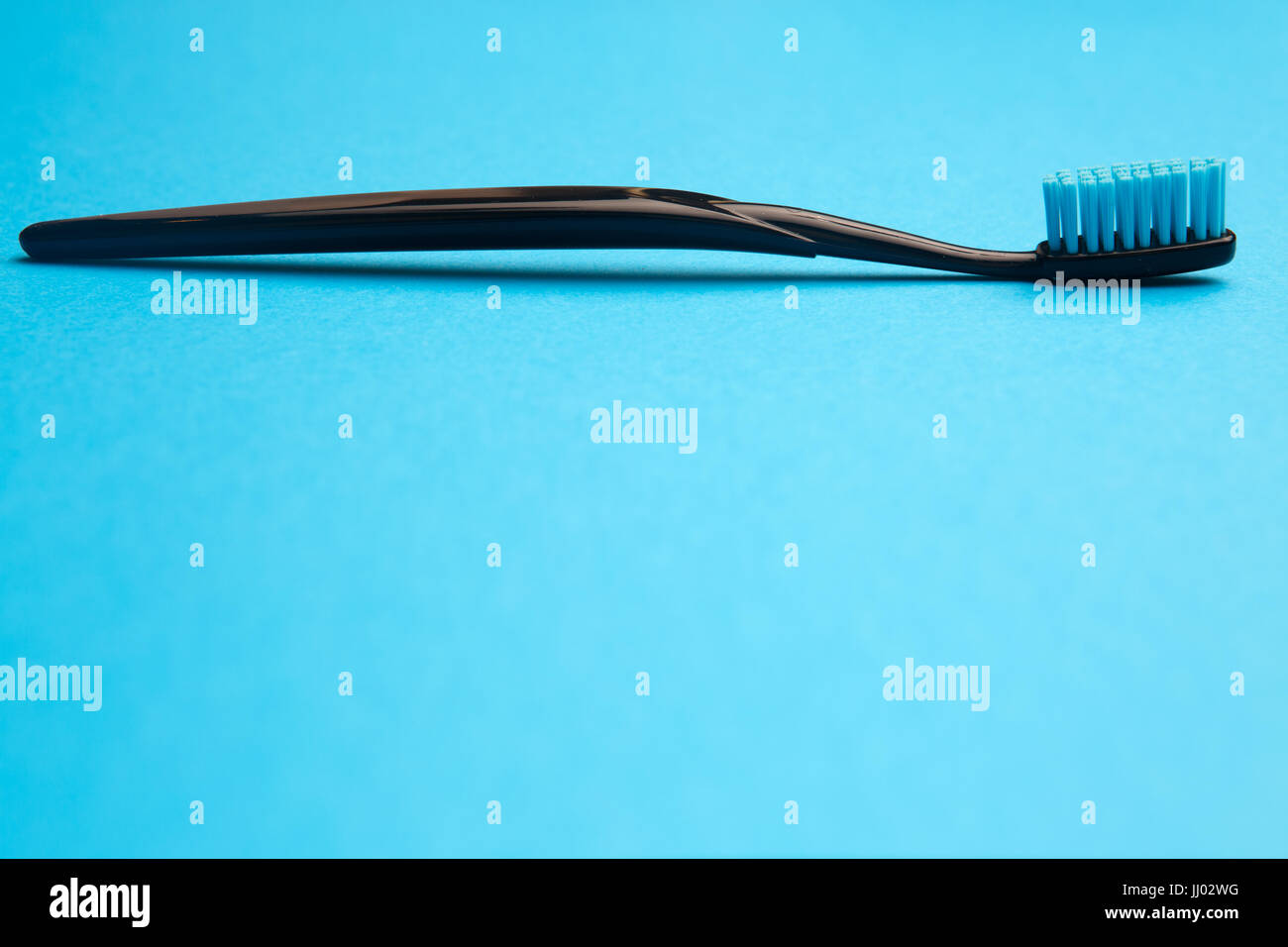 Photo of black toothbrush with blue bristle on empty background, place ...