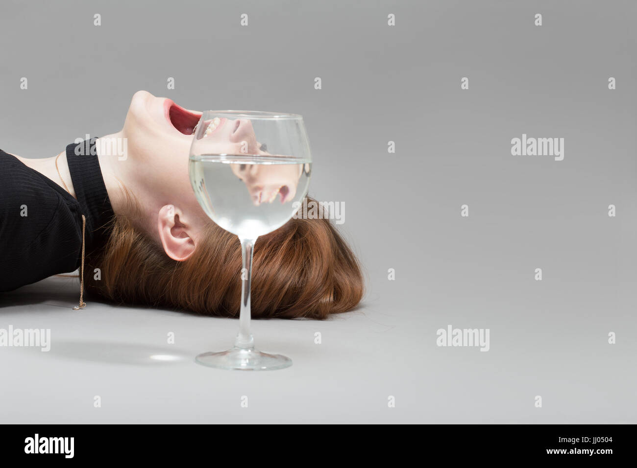 sad girl screaming profile and glass with water on gray background with ...