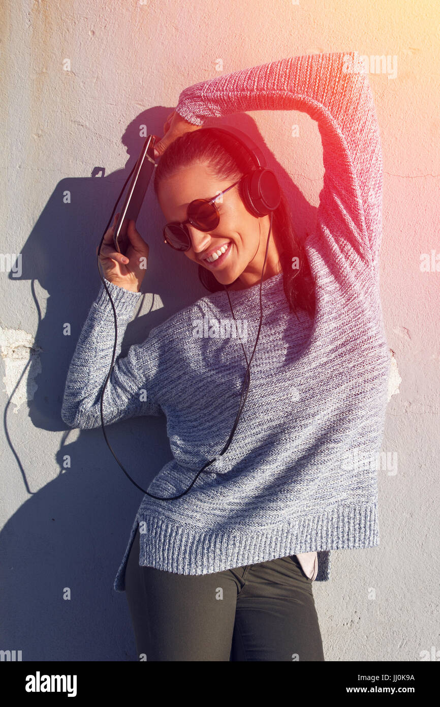 Happy young woman enjoying music in sunset at wall Stock Photo - Alamy