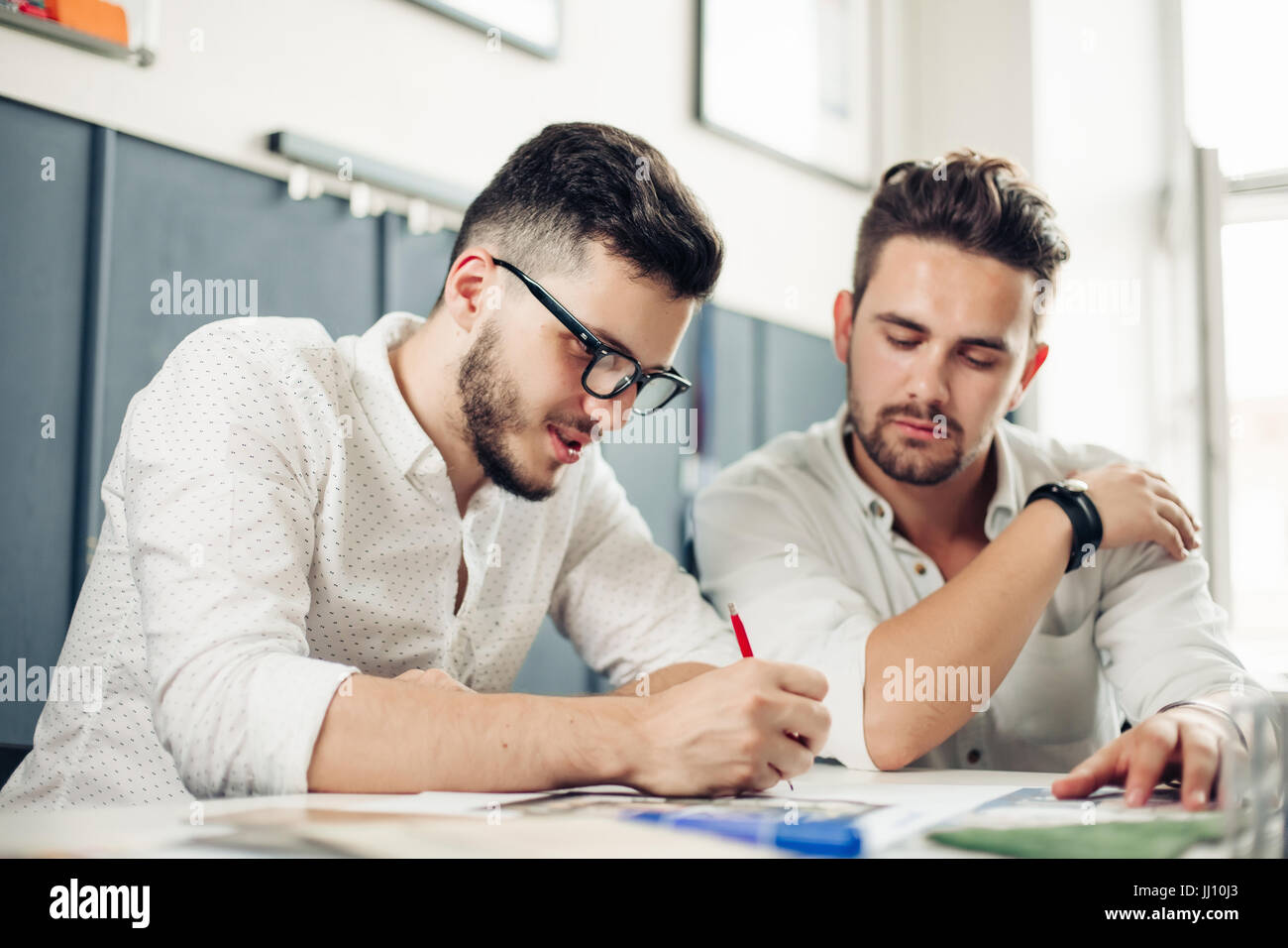 two handsome men architect looking at plans Stock Photo - Alamy