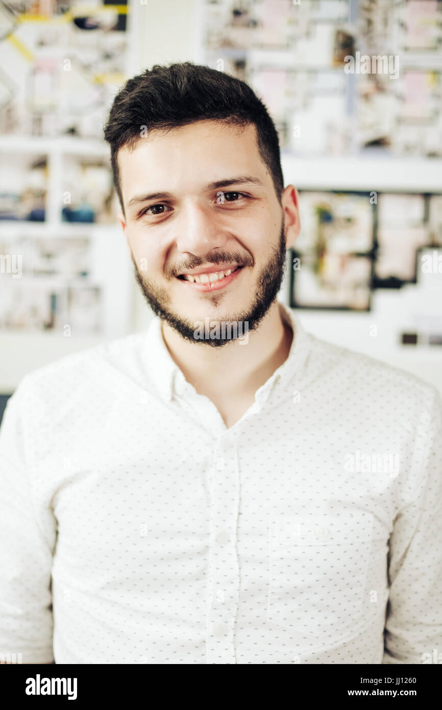 Portrait of a smart young man standing with arms crossed against blue ...