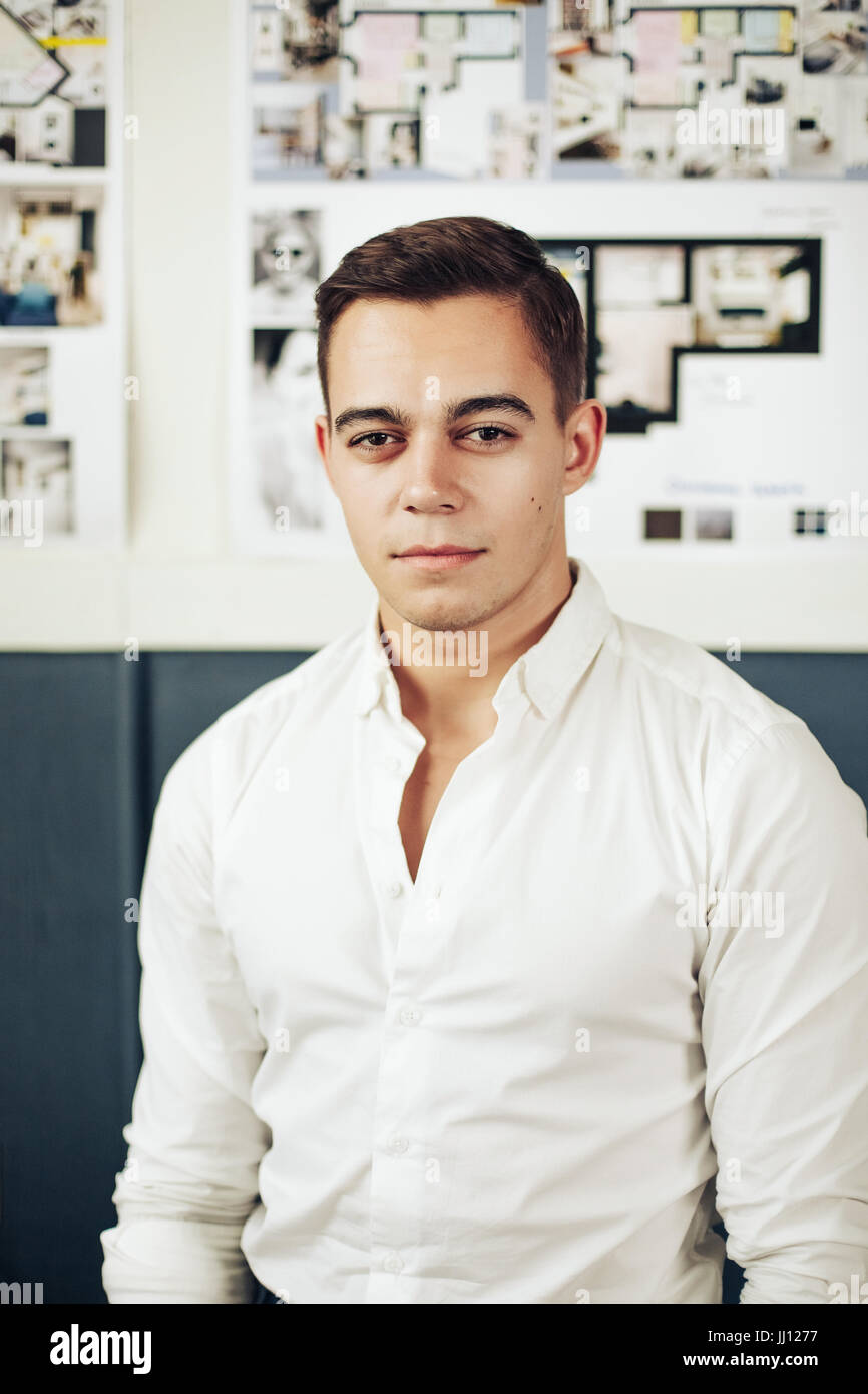 Portrait of a smart young man standing with arms crossed against blue ...