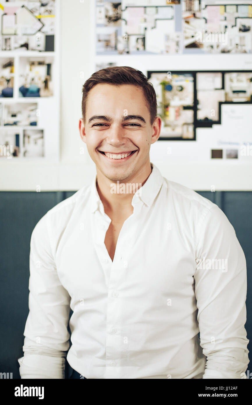 Portrait of a smart young man standing with arms crossed against blue ...