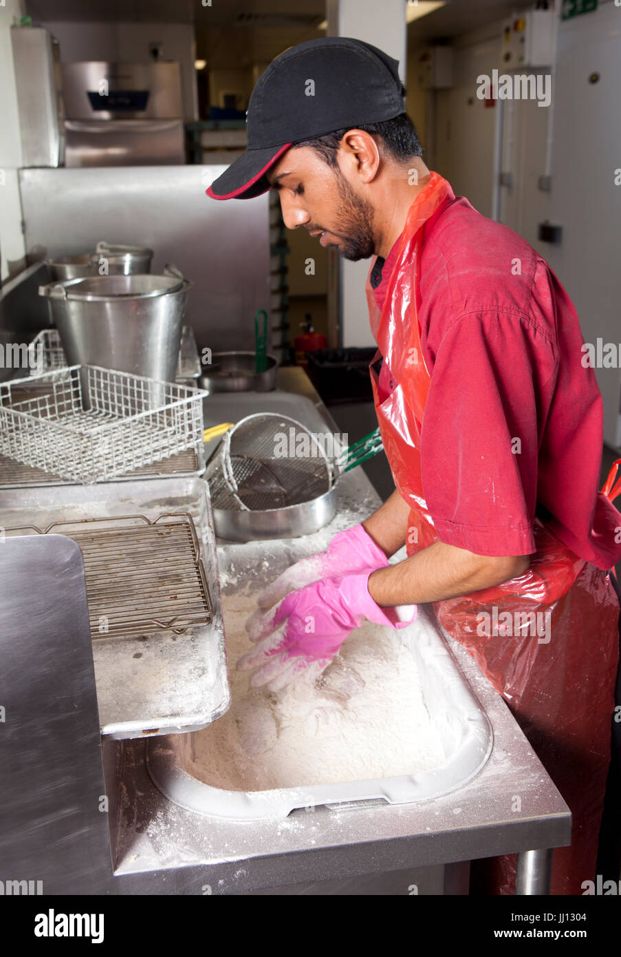 A member of staff prepares fried chicken at a KFC in England, UK Stock ...