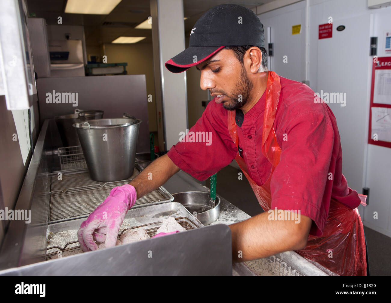 A member of staff prepares fried chicken at a KFC in England, UK Stock ...