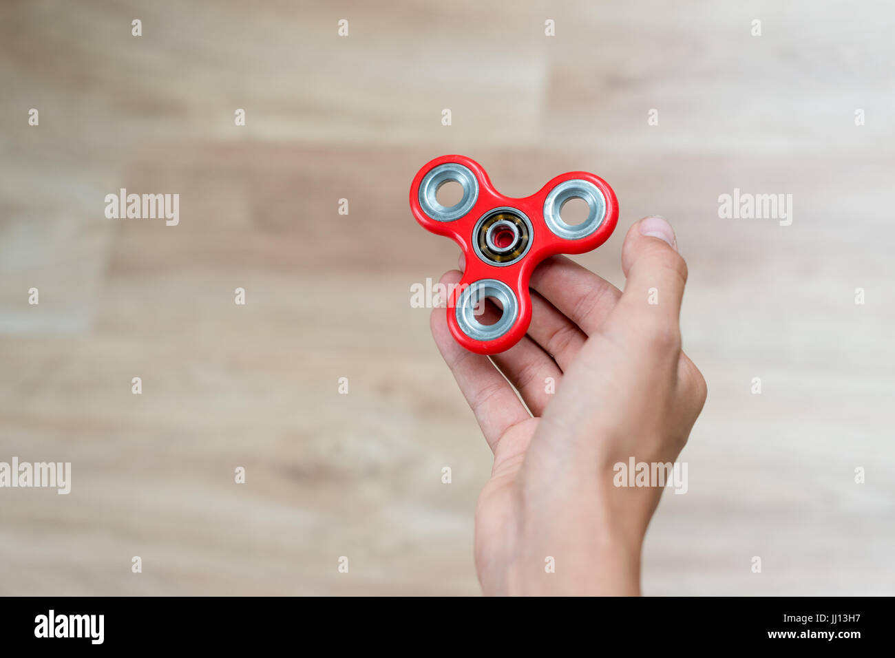 Fidget spinner. Red hand spinner, fidgeting hand toy rotating on child ...