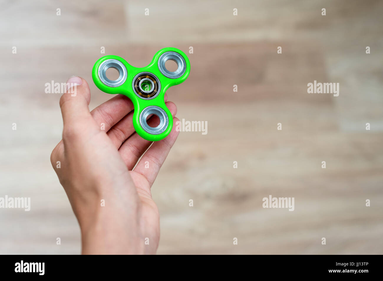 Fidget spinner. Green hand spinner, fidgeting hand toy rotating on ...