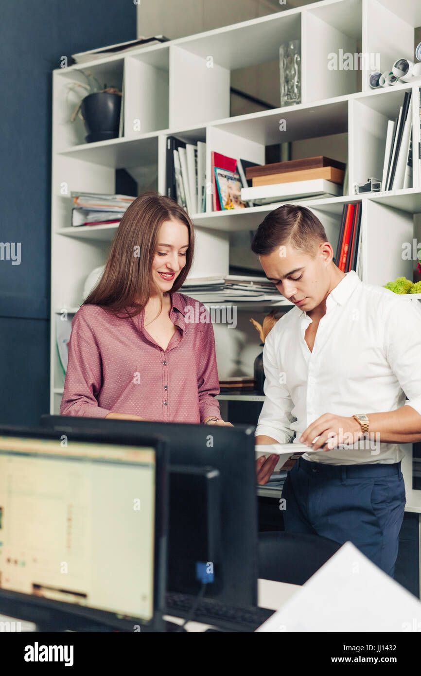 Two male international students reading book about marketing together ...