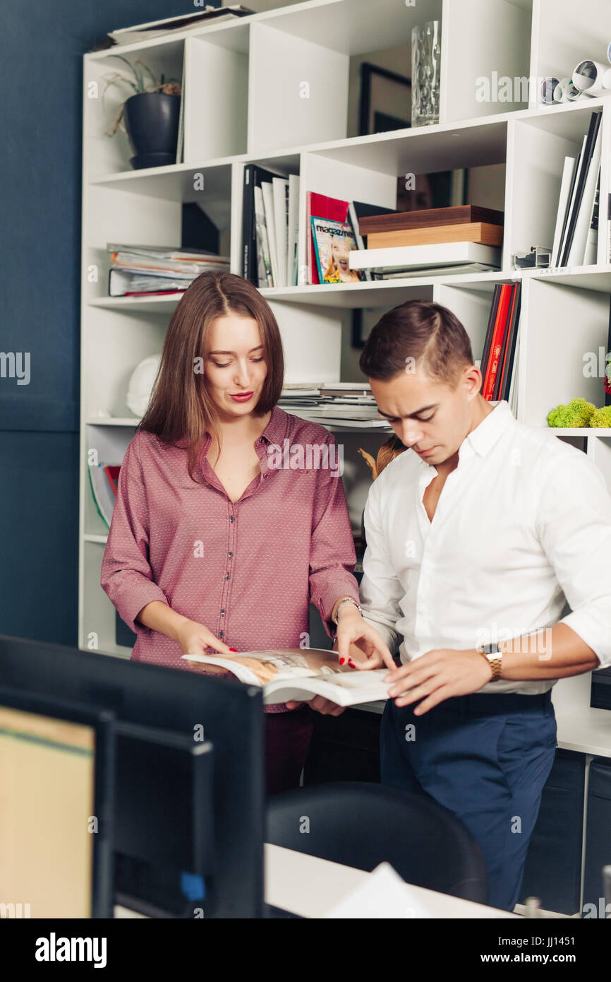 Two male international students reading book about marketing together ...