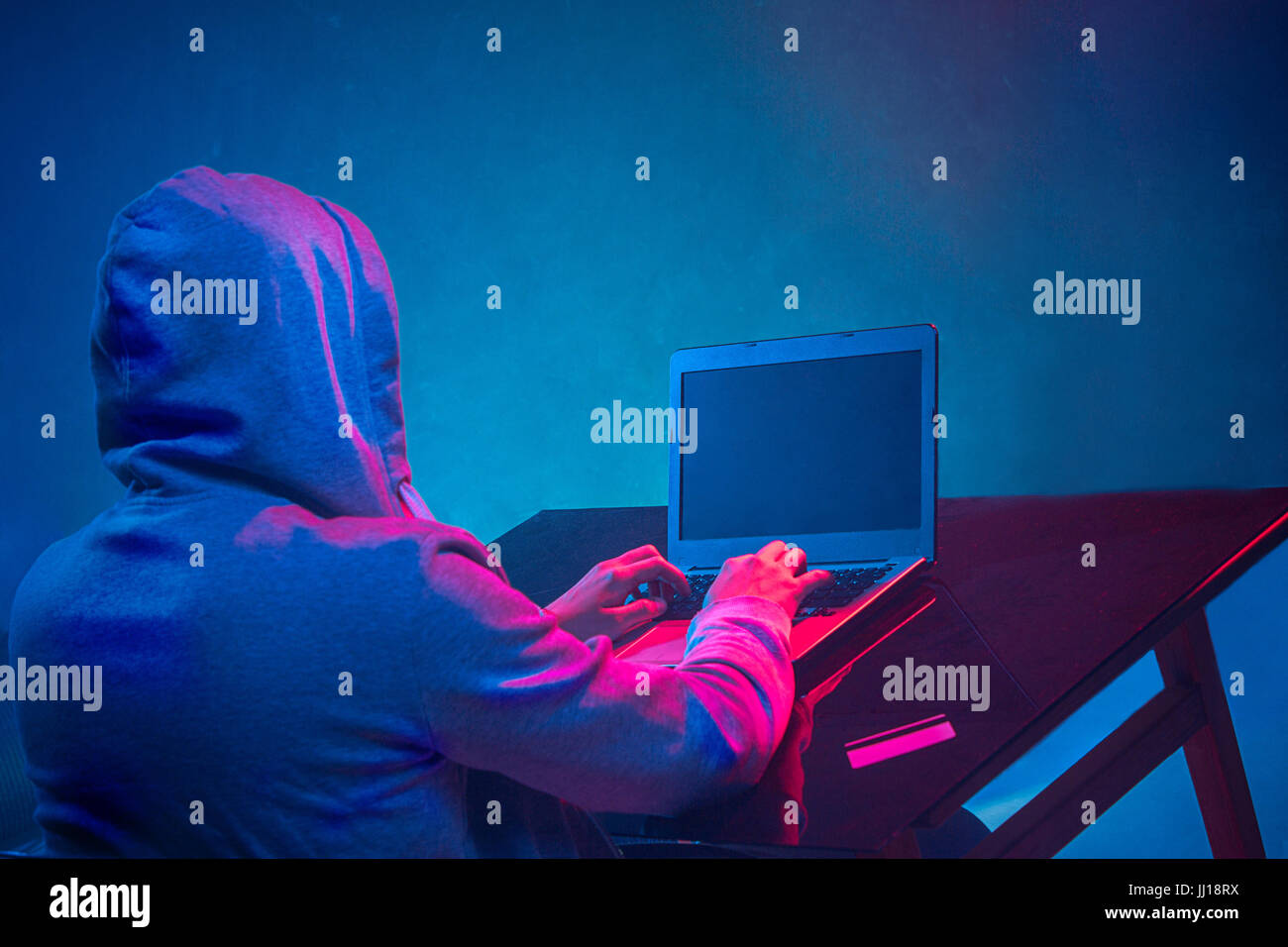 Hooded computer hacker stealing information with laptop Stock Photo - Alamy