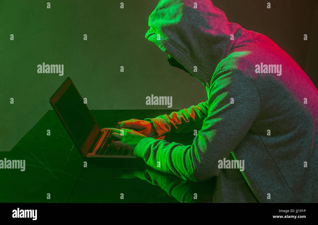 Hooded computer hacker stealing information with laptop Stock Photo - Alamy