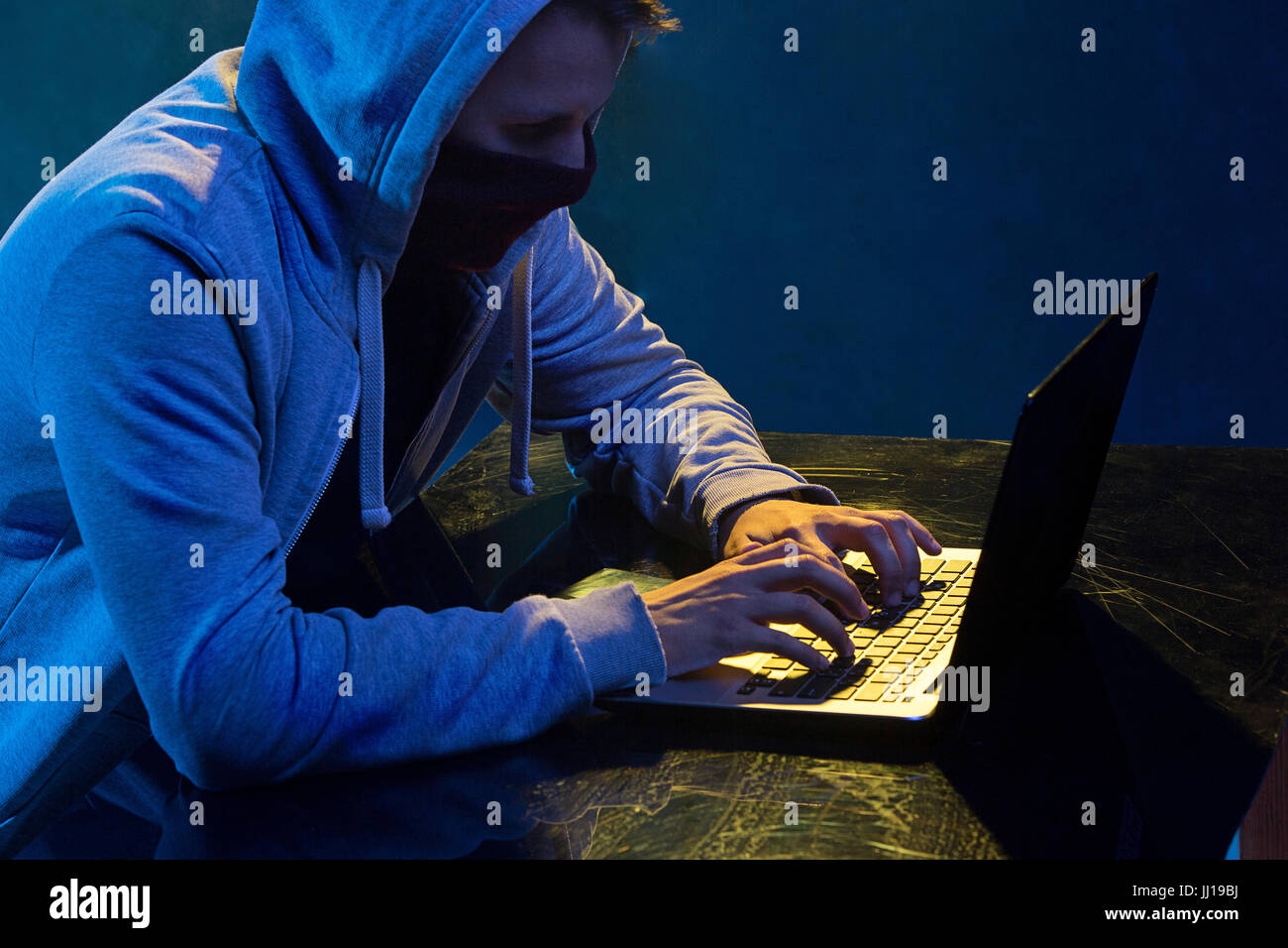 Hooded computer hacker stealing information with laptop Stock Photo - Alamy
