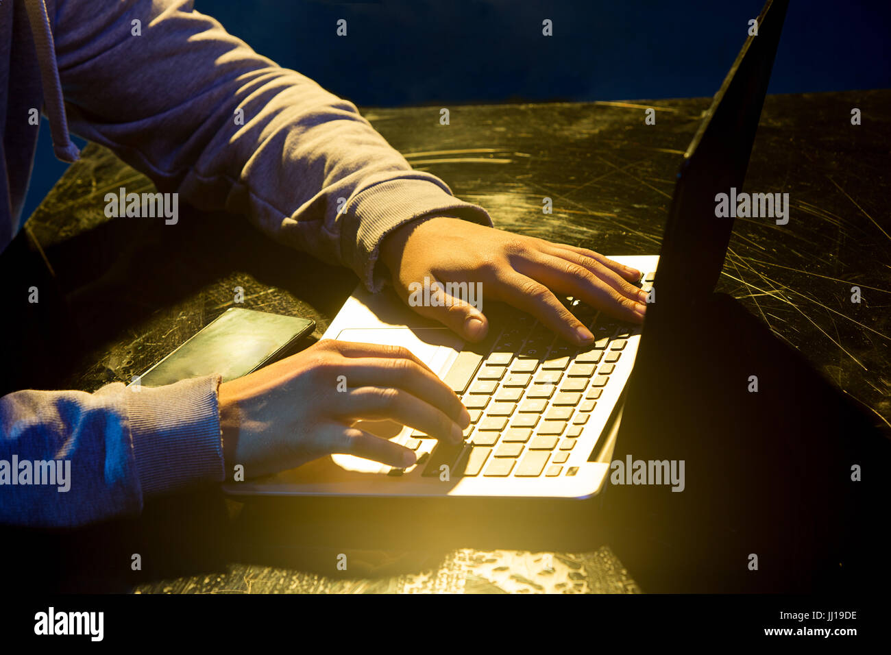 Hooded computer hacker stealing information with laptop Stock Photo - Alamy