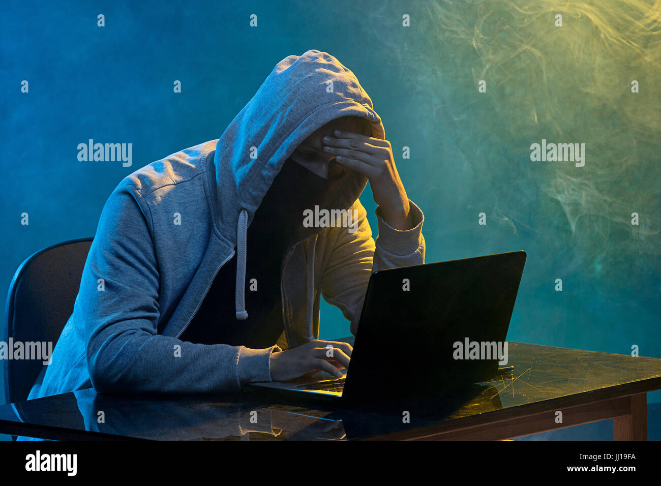 Hooded computer hacker stealing information with laptop Stock Photo - Alamy