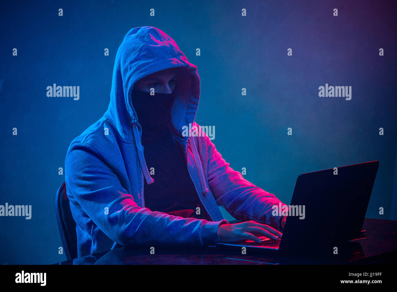 Hooded computer hacker stealing information with laptop Stock Photo - Alamy