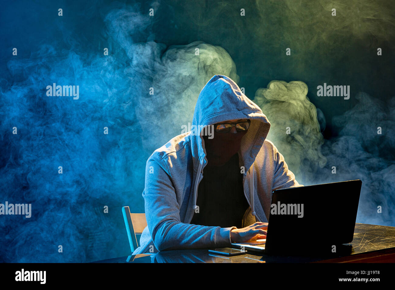 Hooded computer hacker stealing information with laptop Stock Photo - Alamy Hooded computer hacker stealing information with laptop Stock Photo - Alamy