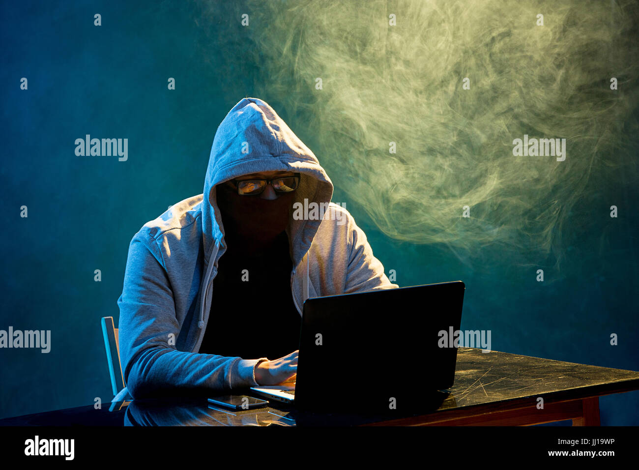 Hooded computer hacker stealing information with laptop Stock Photo - Alamy